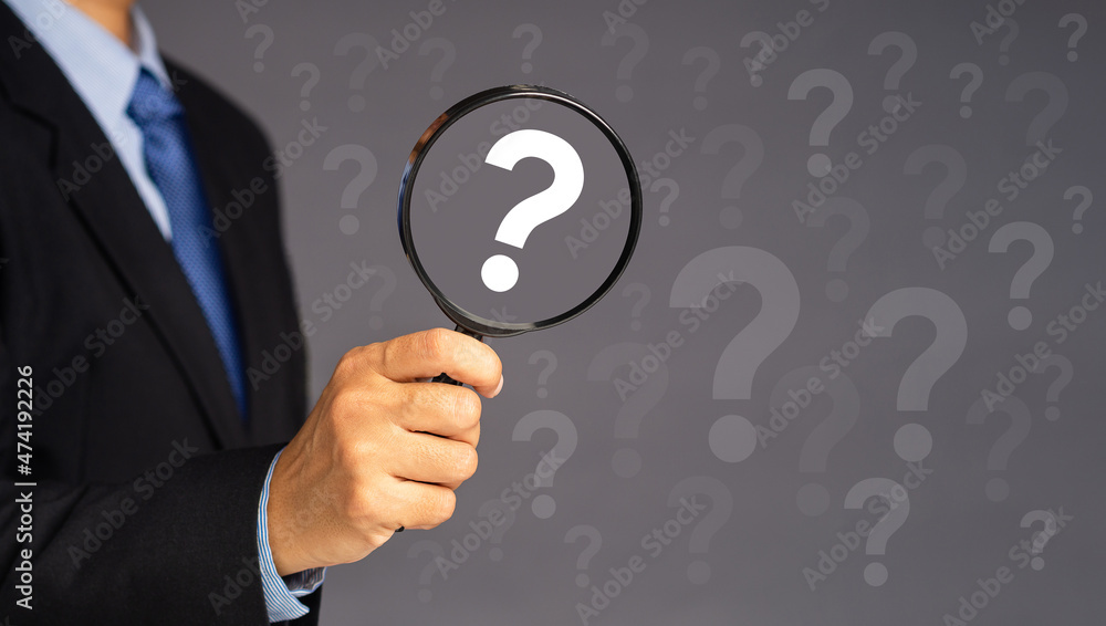 A businessman in a suit holding a magnifying glass look at a white ...