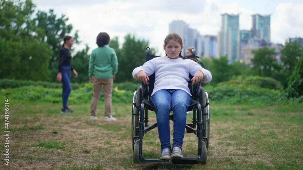 Wide shot depressed disabled girl in wheelchair looking at camera with ...