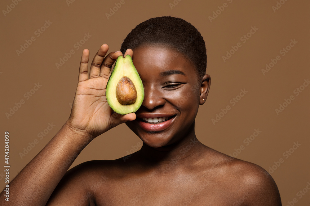 Attractive Nude Black Female With Clean Skin Covering Eye With Avocado