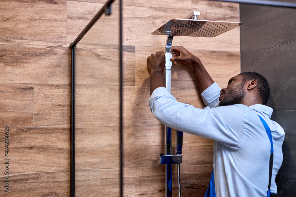 African Professional handyman working in shower bath indoors, side view ...