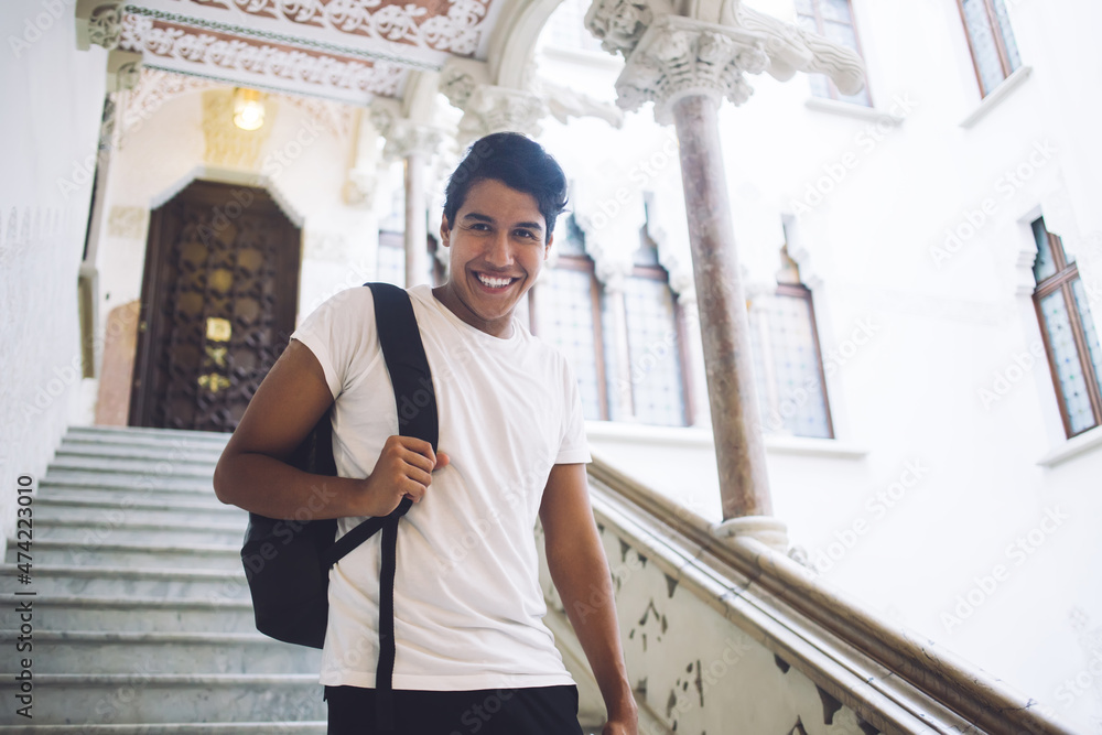 Half length portrait of cheerful Latino student with backpack standing ...