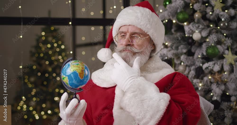 Video Stock Santa Claus sits by a lit Christmas tree in his residence ...