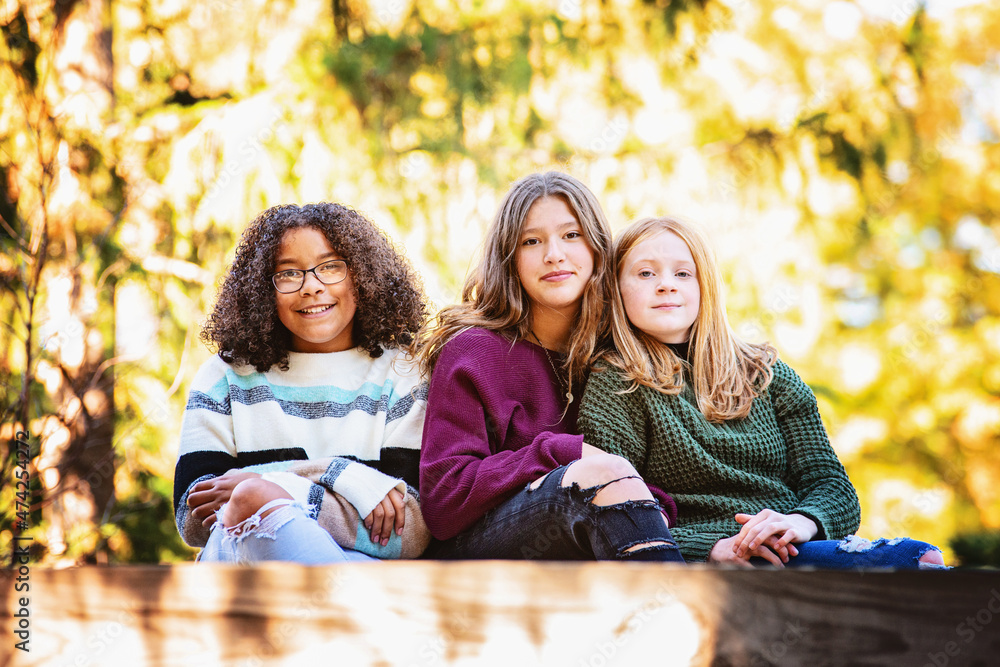 Three pretty tween girls laughing together outdoors in fall colors ...