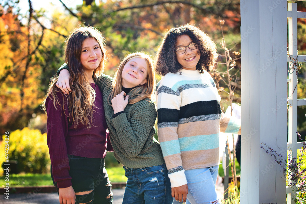 Three pretty tween girls laughing together outdoors in fall colors ...