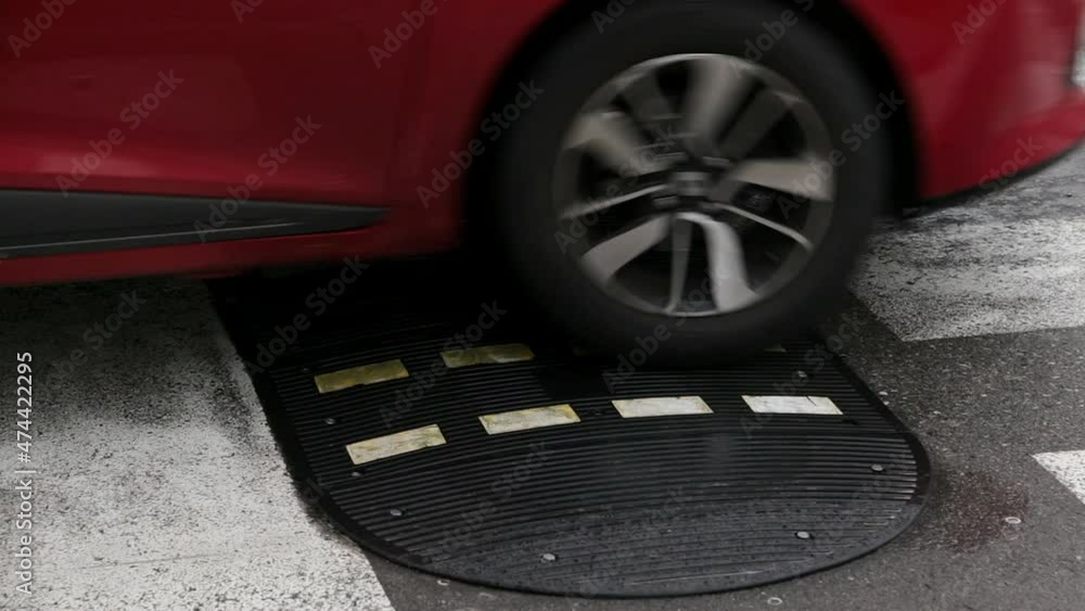Cars on a speed bump before crosswalk. Wheels of the vehicles going ...