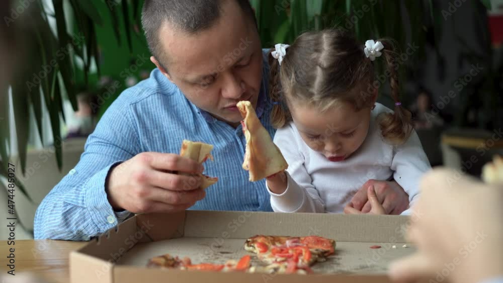 dad and little daughter are eating Italian pizza in a cafe, family in a ...