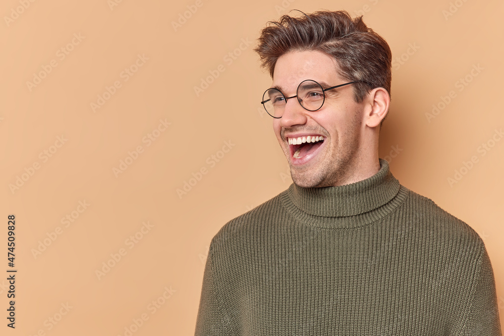 Positive joyful guy looks away happily keeps mouth opened laughs at ...