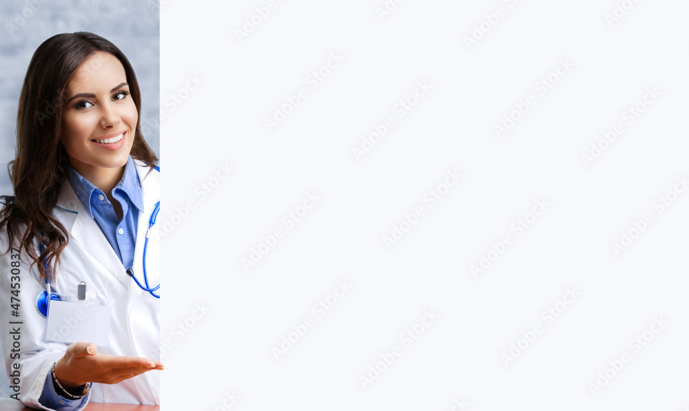 Portrait of happy smiling female doctor showing mockup blank sign board ...