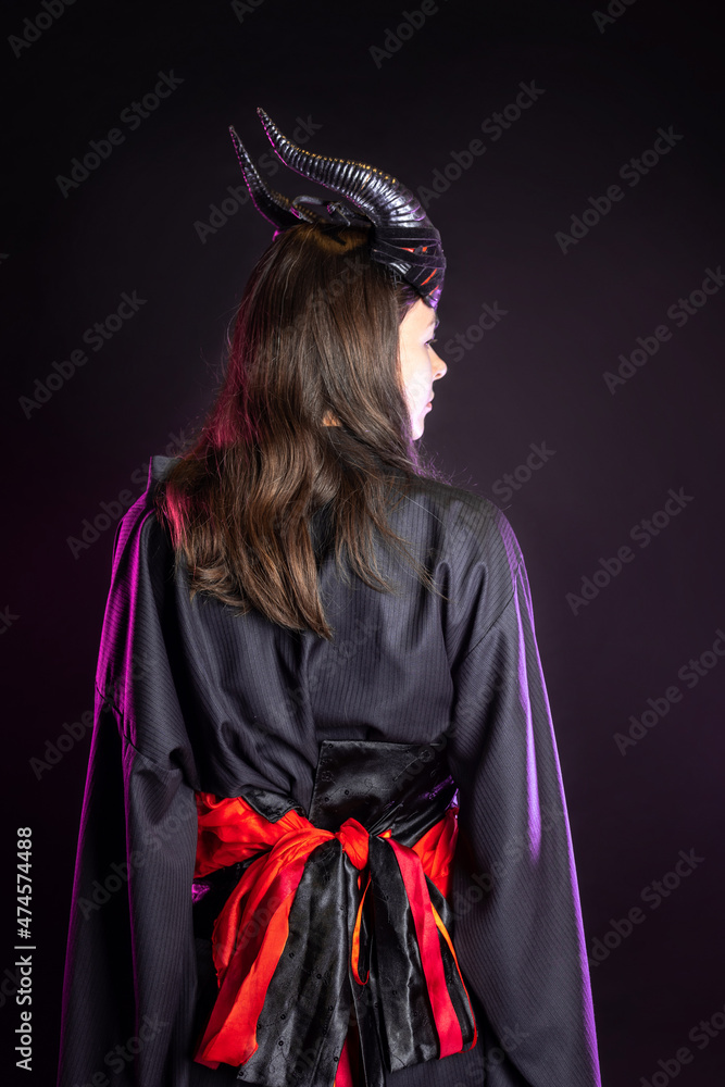 A demoness with horns and in a black kimono with a red belt, a costume ...