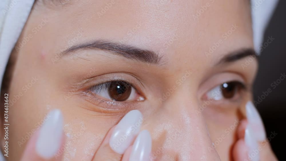 A beautiful female model applying moisturizer under her eyes in the ...