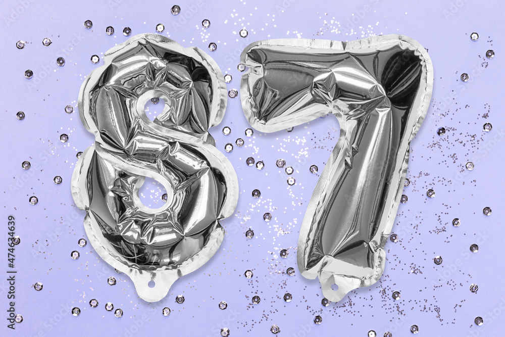Silver foil balloon number, digit eighty seven on a lilac background ...