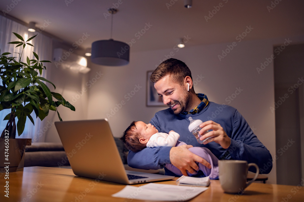 Fatherhood and work from home. A young working father holding his baby ...