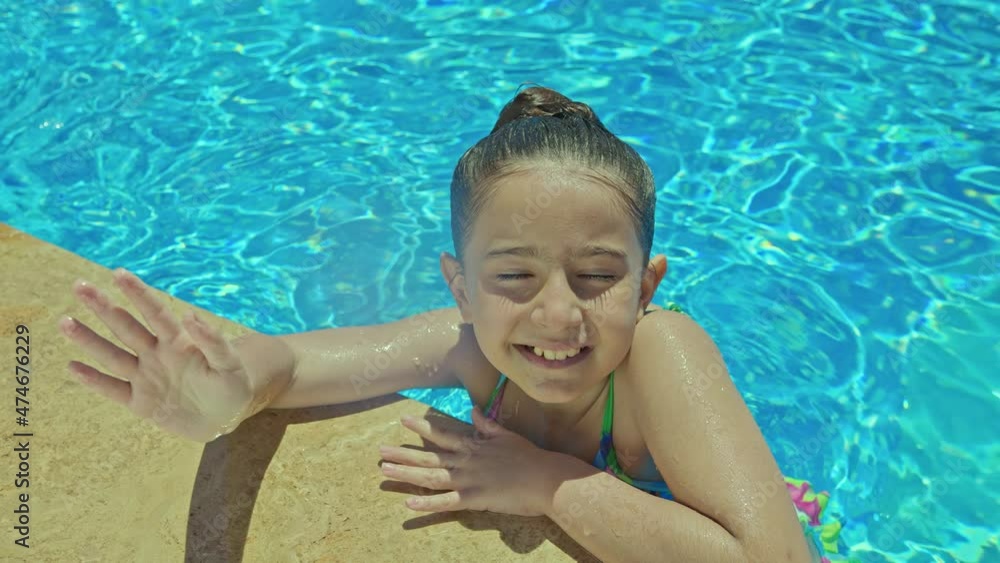 Vidéo Stock Little beautiful girl swimming in the pool, playing in the ...