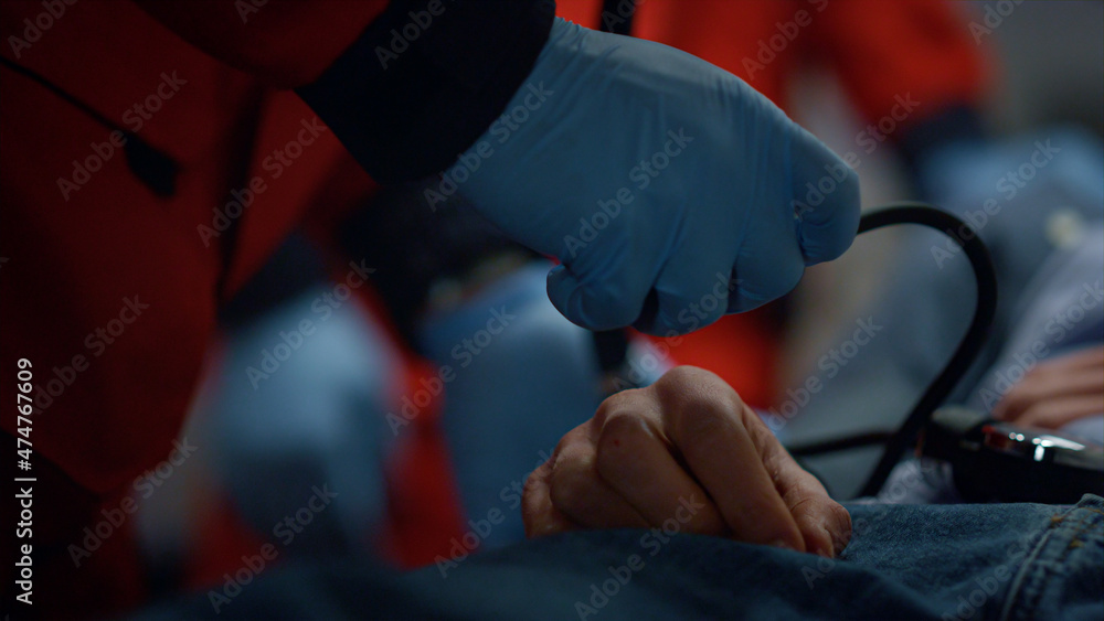 Paramedic hands in gloves measuring patient blood pressure with ...