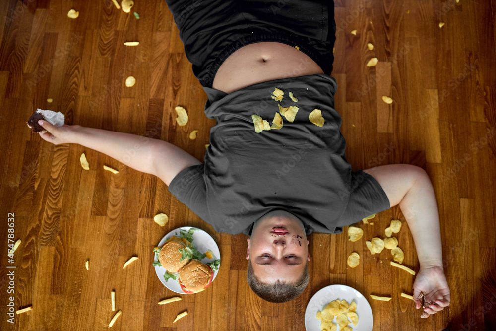 Top view on glutton teen boy surrounded by junk food, overeating ...