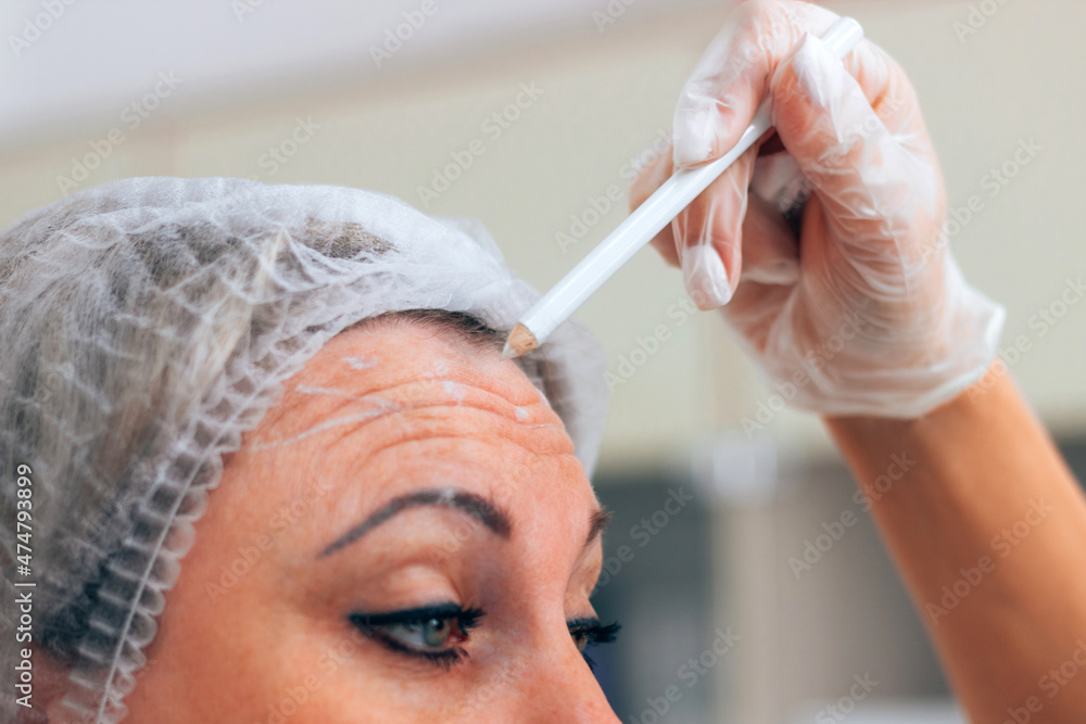 Marking by a master beautician of the forehead and between the eyebrows ...