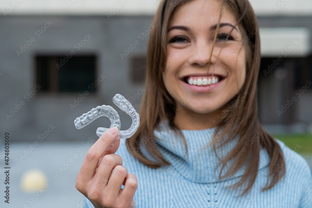 Caucasian woman with white smile holding transparent removable retainer ...