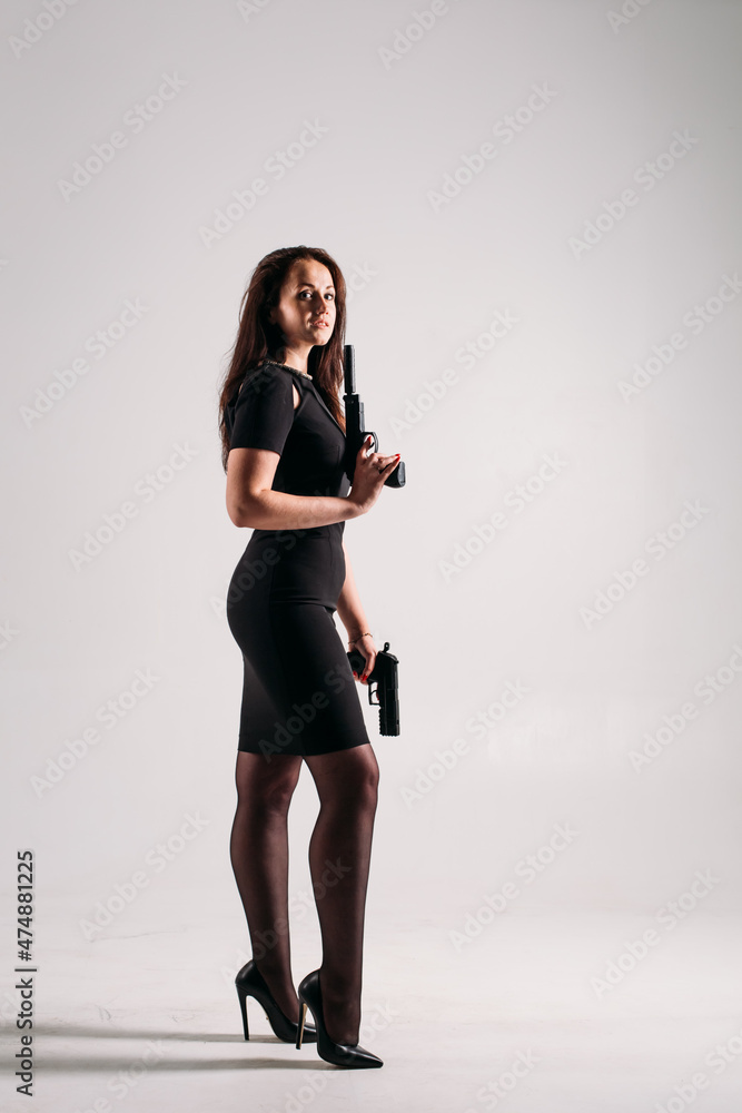 young girl in a black suit with a pistol in her hands on a white ...
