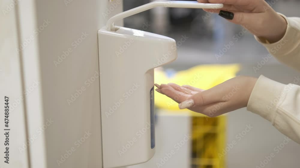 Female hands washing under an automatic alcoholic sanitizer dispensary ...