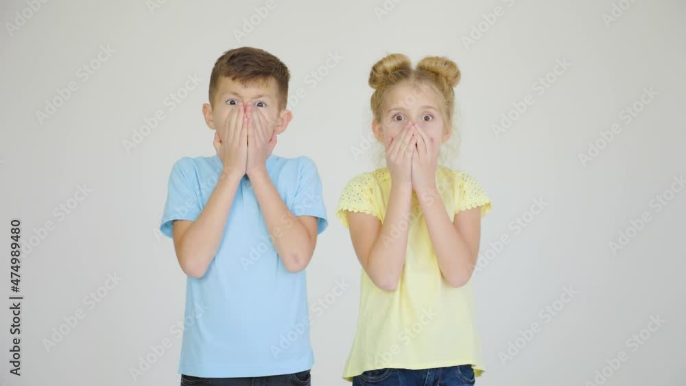 two surprised children shocked with their hands in their mouths ...
