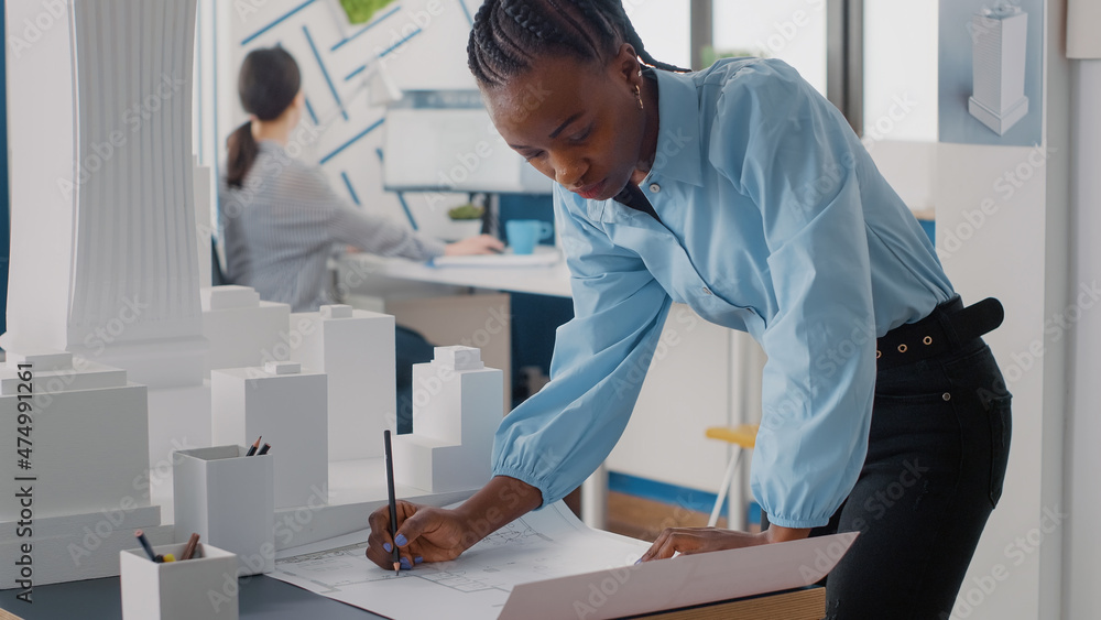 Engineer working on blueprints plans on desk to design building model ...