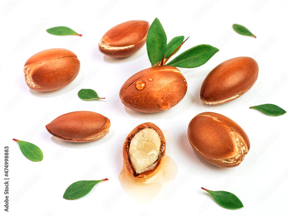 Argan nuts with green leaves on an isolated white background. Chopped ...
