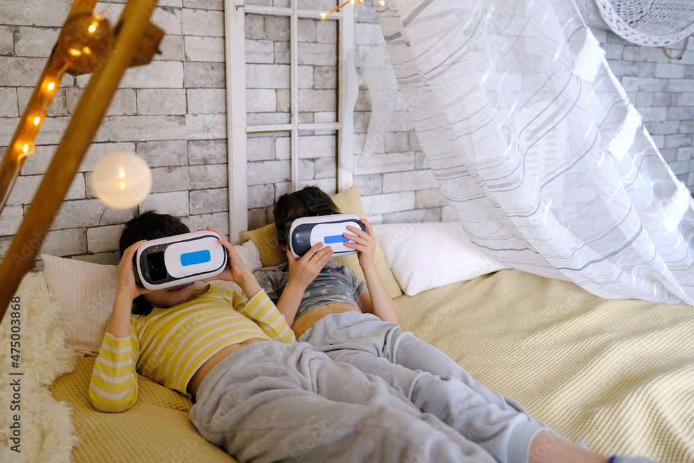 two children 8-10 years old, boys lying on bed in tent in modern VR ...