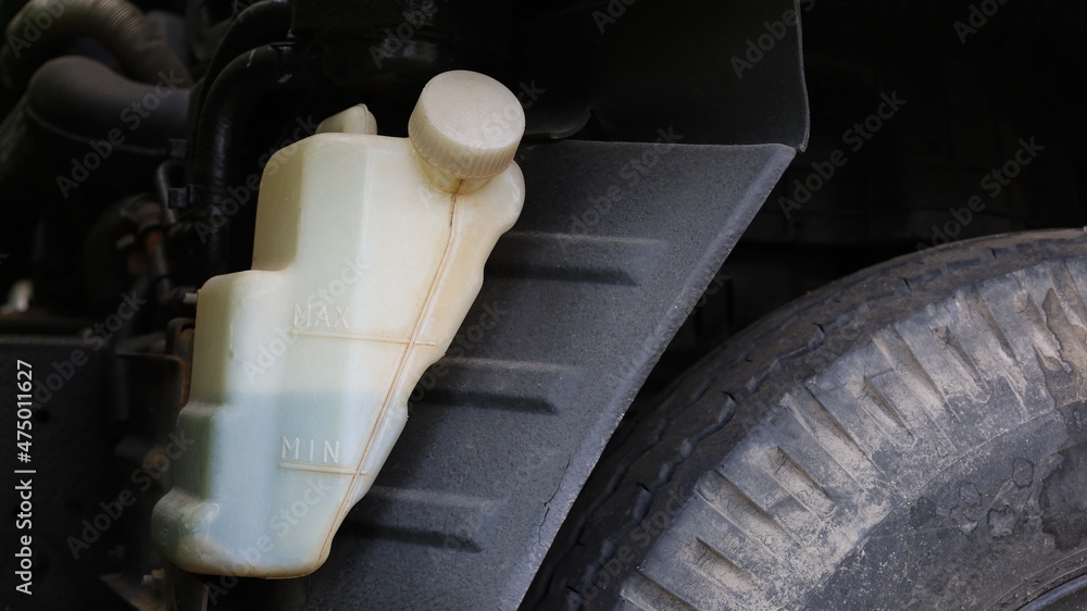 Truck coolant tank. The white plastic tank has coolant in the engine ...
