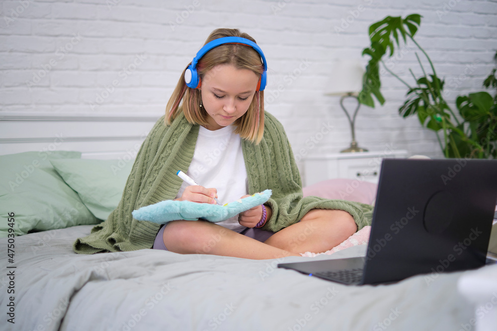 Teenage girl doing homework on the bed. teen girl school student write ...
