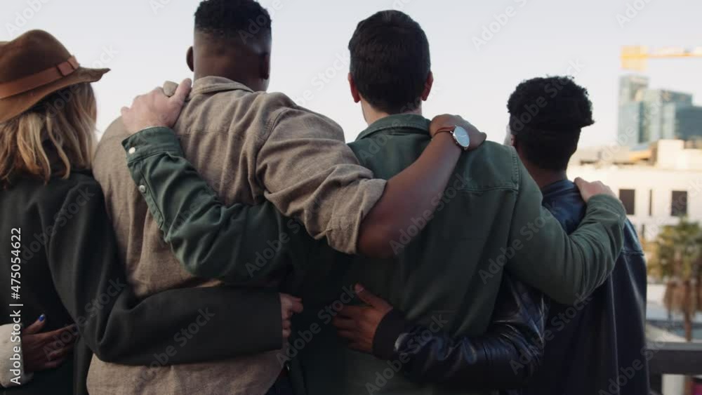 Diverse group of young adult friends arm in arm looking at the view ...