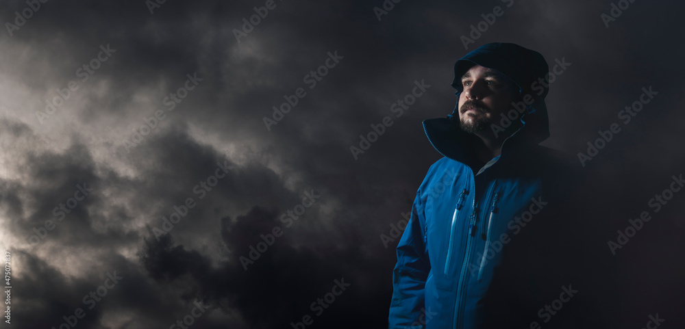 Weather forecast concept. A hopeful young man in a rain jacket awaiting ...