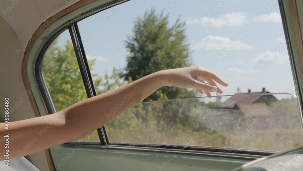 Close-up of the bride's hand sticking out the window of a retro car ...