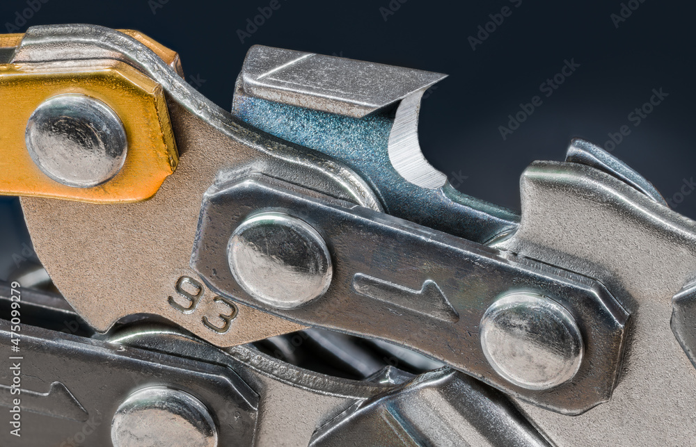 Sharp steel tooth of chainsaw chain detail on dark blue background ...