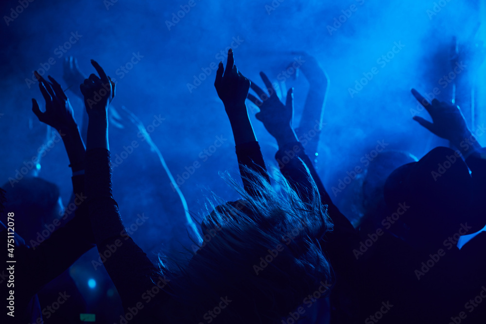 Silhouettes of young people jumping and raising hands while enjoying ...