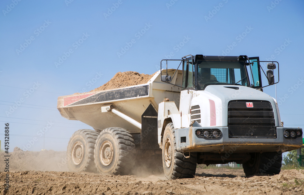 large gray articulated dumper at a construction site drives down a ...