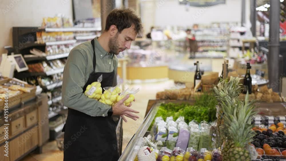 Grocery store worker caucasian bearded guy arranging packed potato in ...