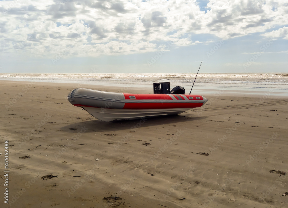 Rigid hull inflatable boat with outboard motor in the shore beaten by ...