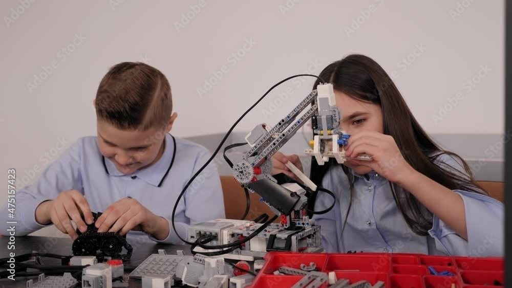 Children make a robot out of a robotic constructor at a desk with a ...