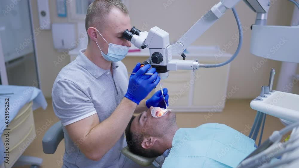 Side view male Caucasian dentist using dental endodontic binocular ...