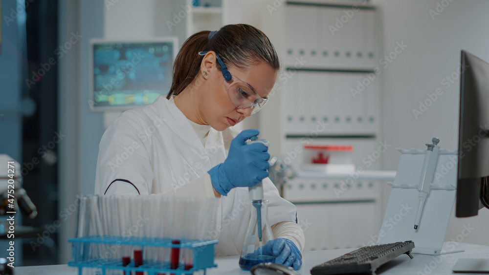 Lab worker using micro pipette with beaker and test tubes to do ...