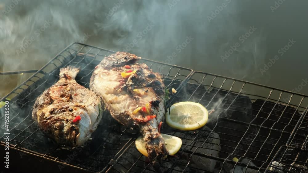 Sea bass or grouper fish grilled over charcoal. Close-up shot cooking ...