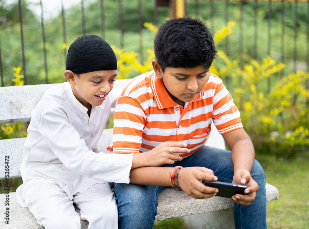 Mutiethnic kids playing video game on mobile phone at park - concept of ...