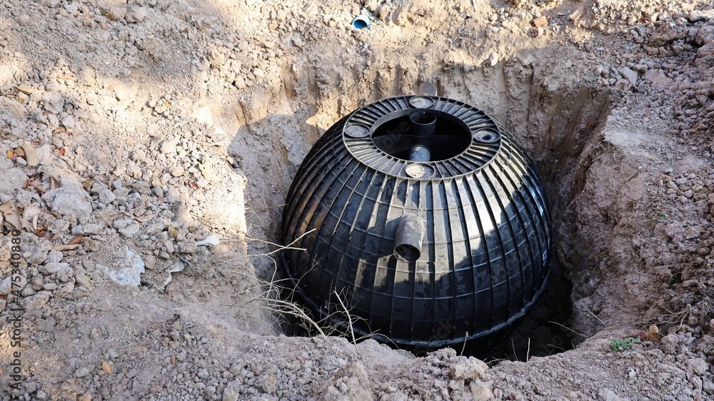 A black septic tank in the pit. Plastic bucket for treating water and ...