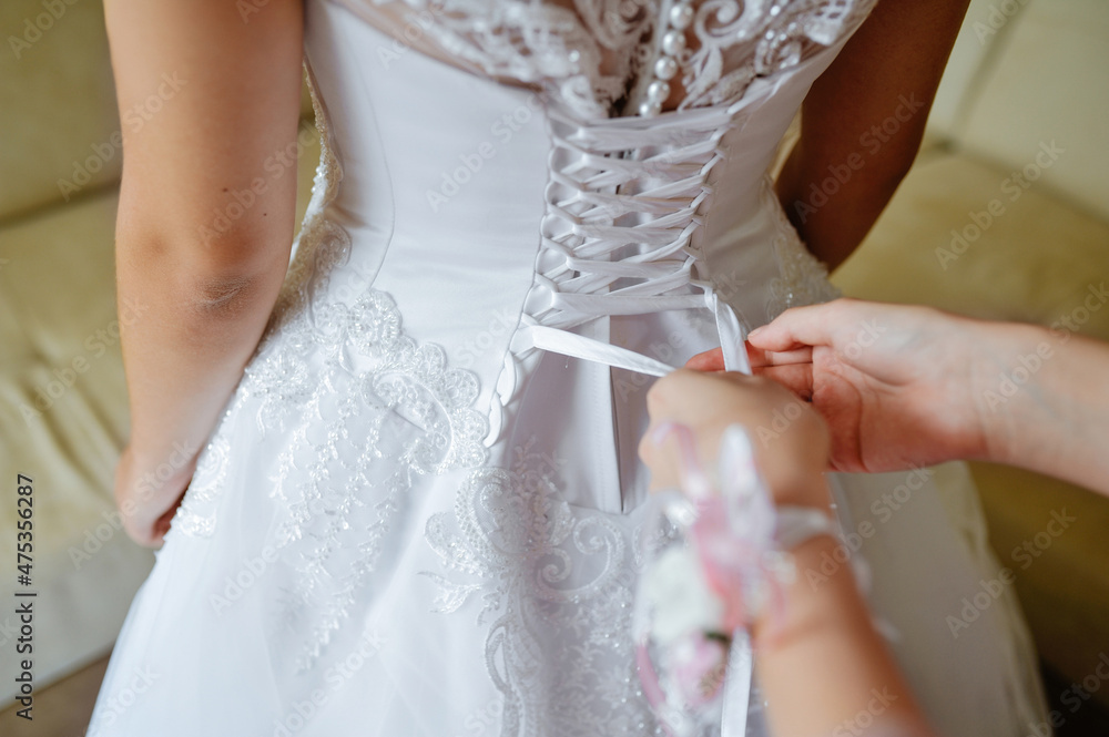 The bridesmaid prepares the bride for the wedding day, helps to button ...