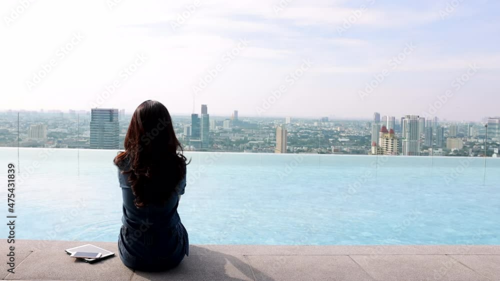 Vidéo Stock Back view of woman sitting on the edge dangling her feet in ...