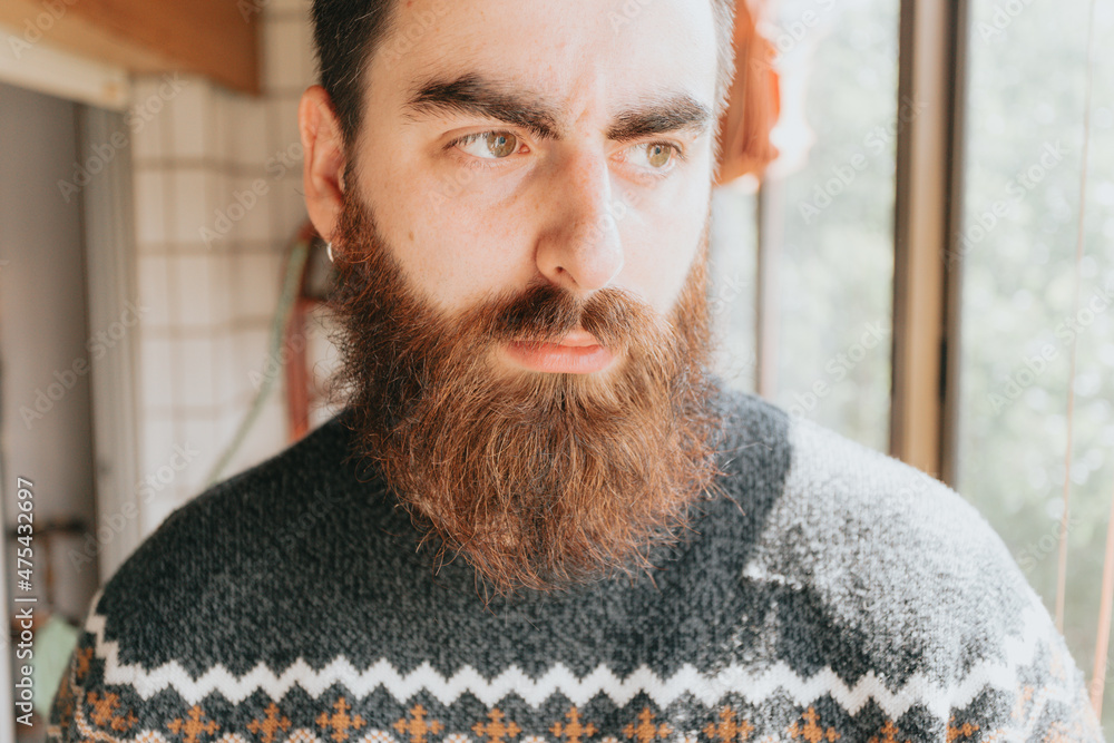 Depressed young bearded handsome man near window at home feeling sad ...