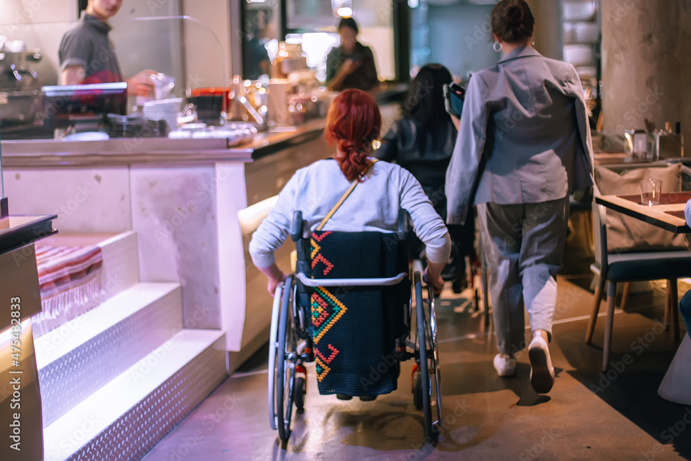 girl in a wheelchair in a cafe near bar. Accessible cafe for people ...