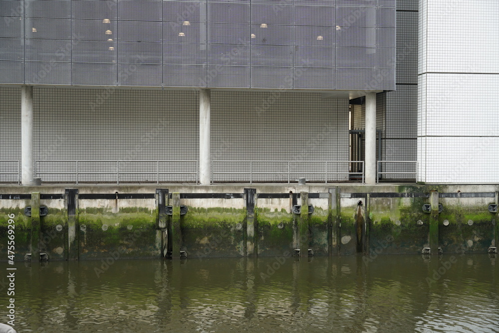 Corporate building above a concrete wall of riverbank in one channel of ...