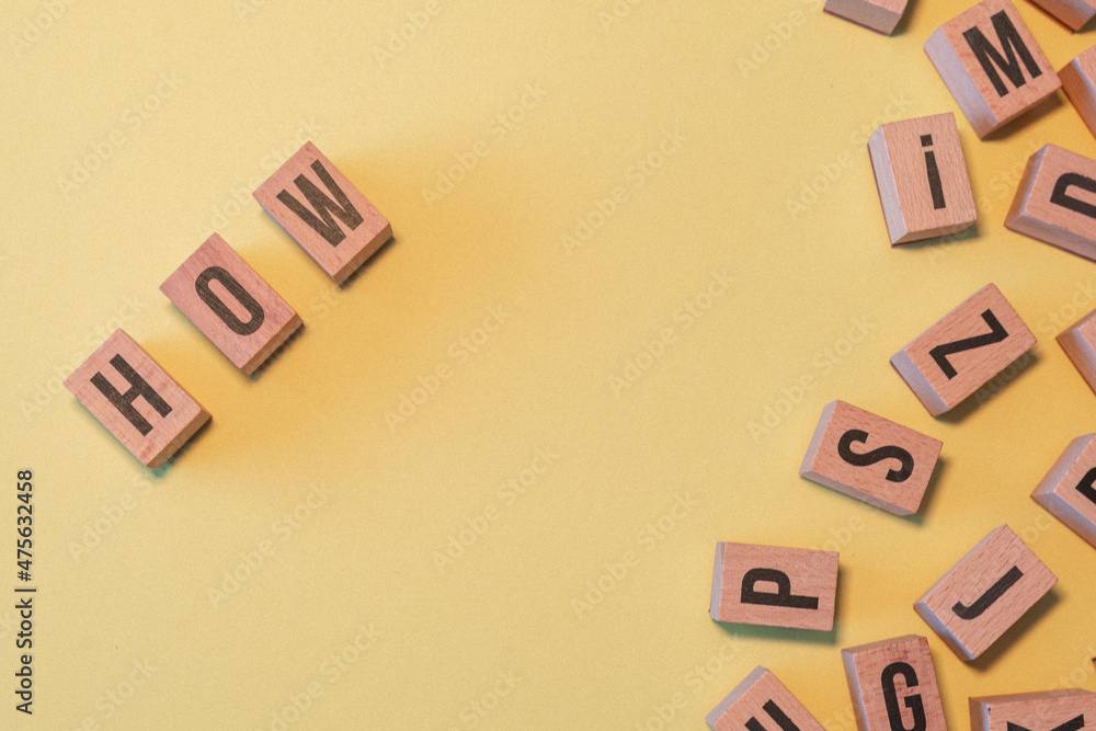 Word HOW taken from a pile of wooden letter blocks in the yellow ...