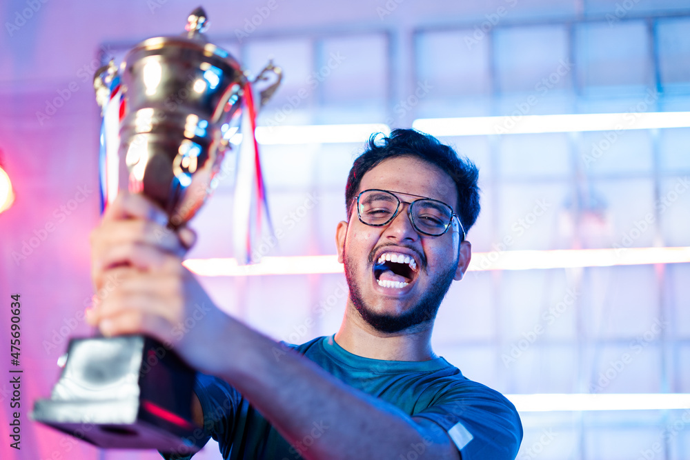 Excited gamer celebrating win by showing trophy to audience and ...